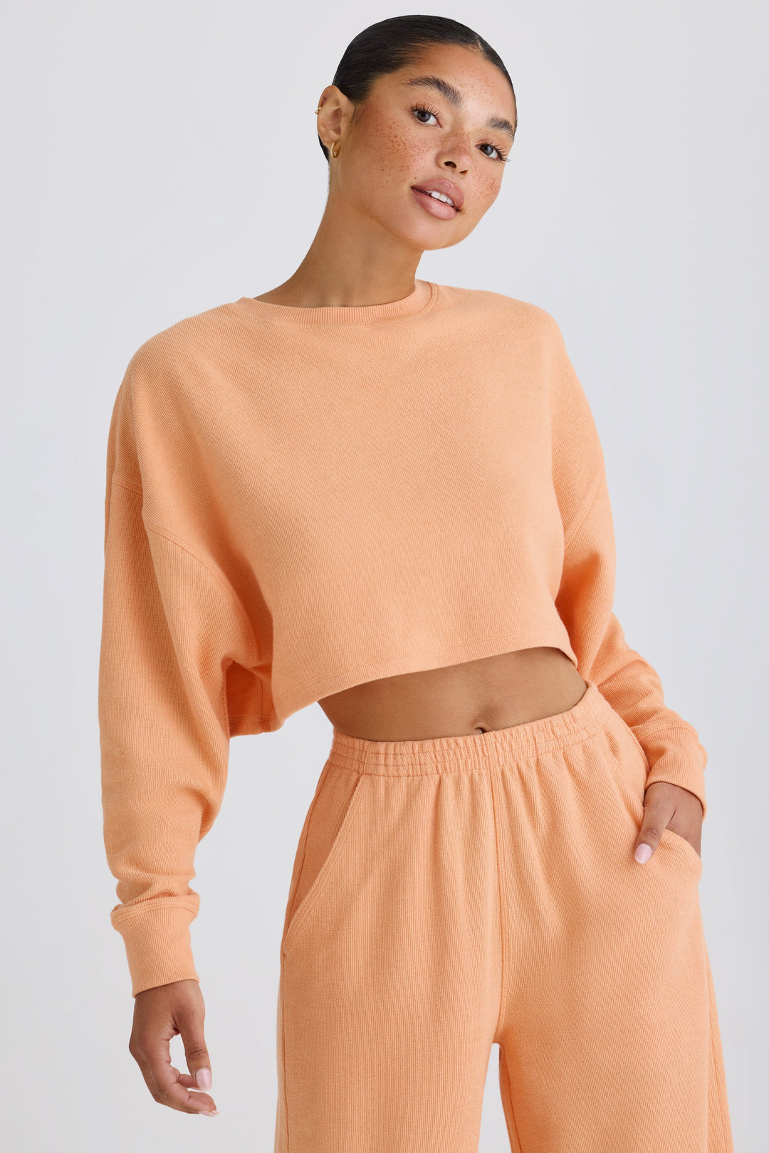 Jet Set Crew-Neck Open-Back Cropped Sweatshirt in Peach | Oh Polly